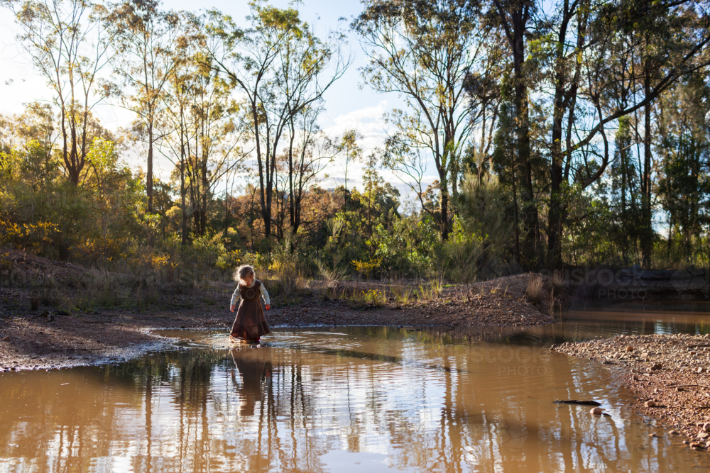 Image of Young Australian child playing beside muddy bushland pool in ...