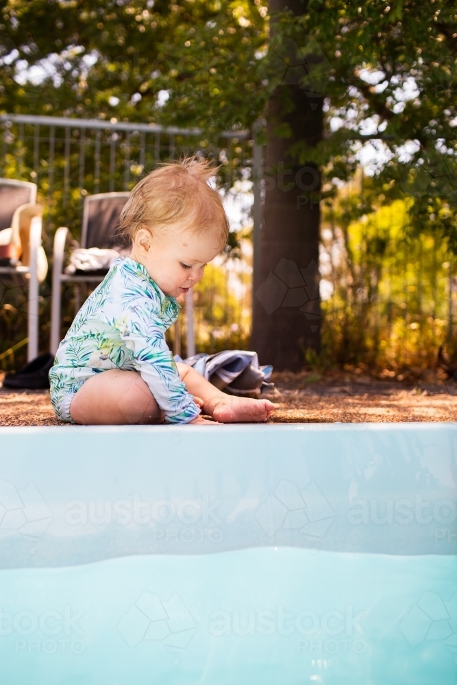 Image of Young baby girl playing at edge of inground backyard pool ...