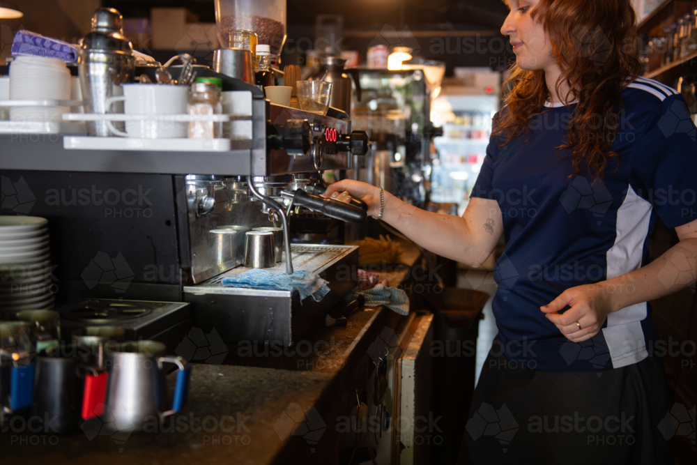 Image of young barista in a cafe behind the coffee machine - Austockphoto