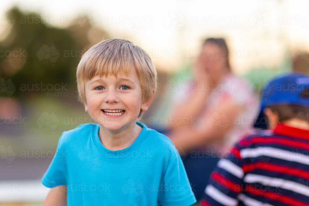 Image of young blond Caucasian boy grinning at viewer with sibling and ...