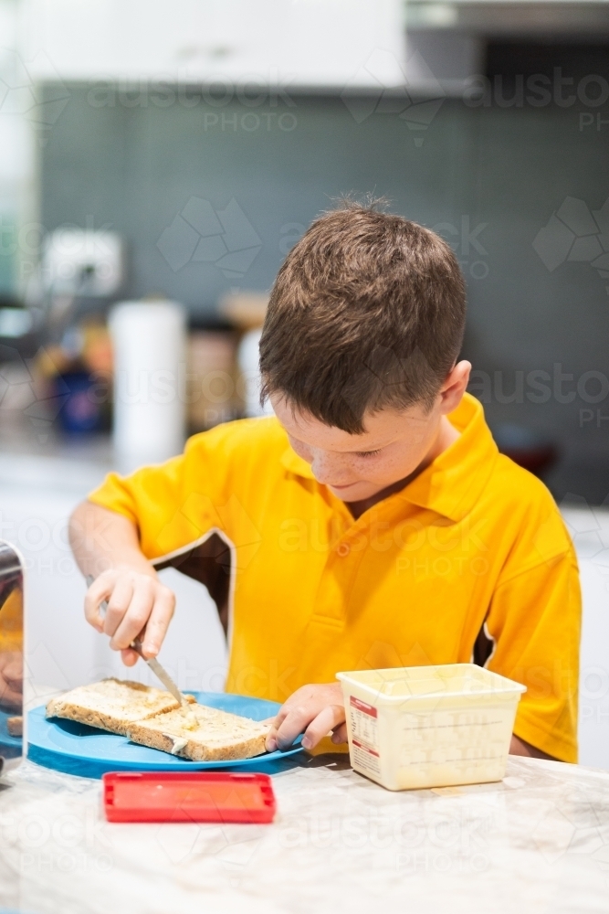 Image of Young boy buttering his toast ready for breakfast before ...