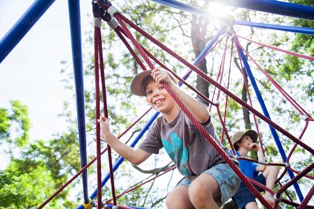 Image of Young boy climbing spiderweb playground equipment at park ...