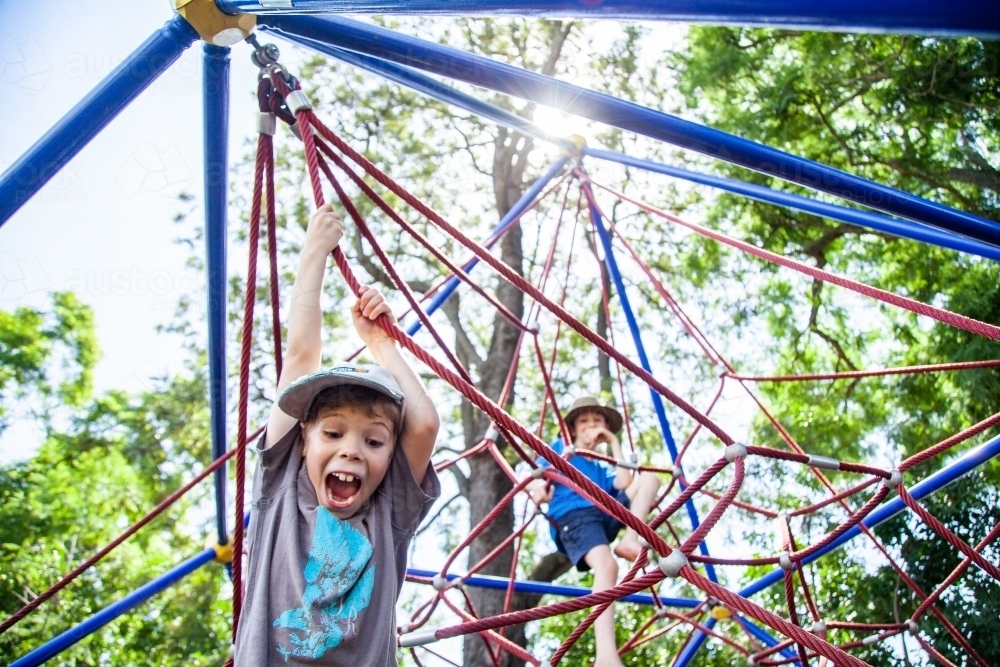 Image of Young boy climbing spiderweb playground equipment at park ...