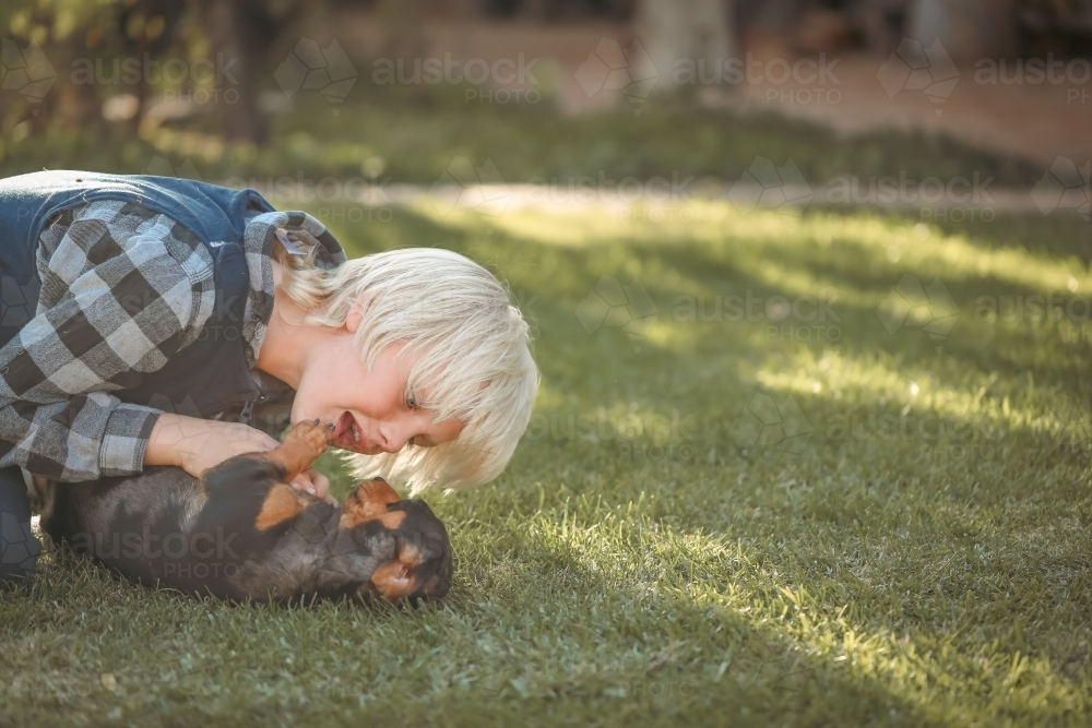 Image of Young boy cuddling dachshund dog on lawn with copy space ...