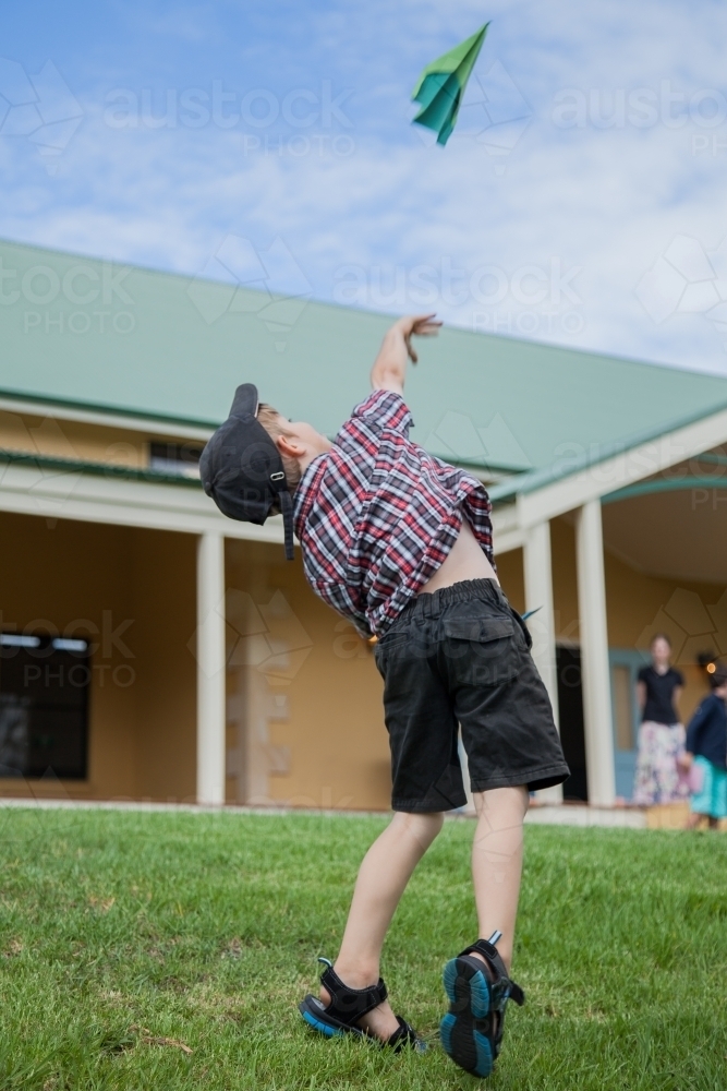 Image of Young boy flying paper plane into the sky - Austockphoto