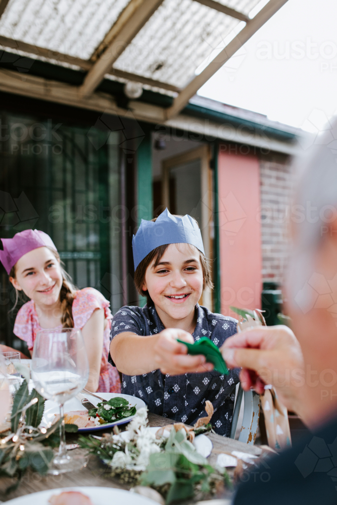 Image of Young boy giving paper hat to grandpa. - Austockphoto