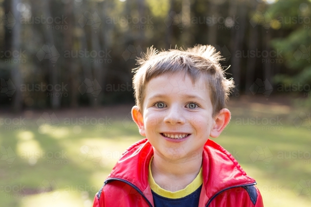 Image of Young boy grinning at camera in forest - Austockphoto