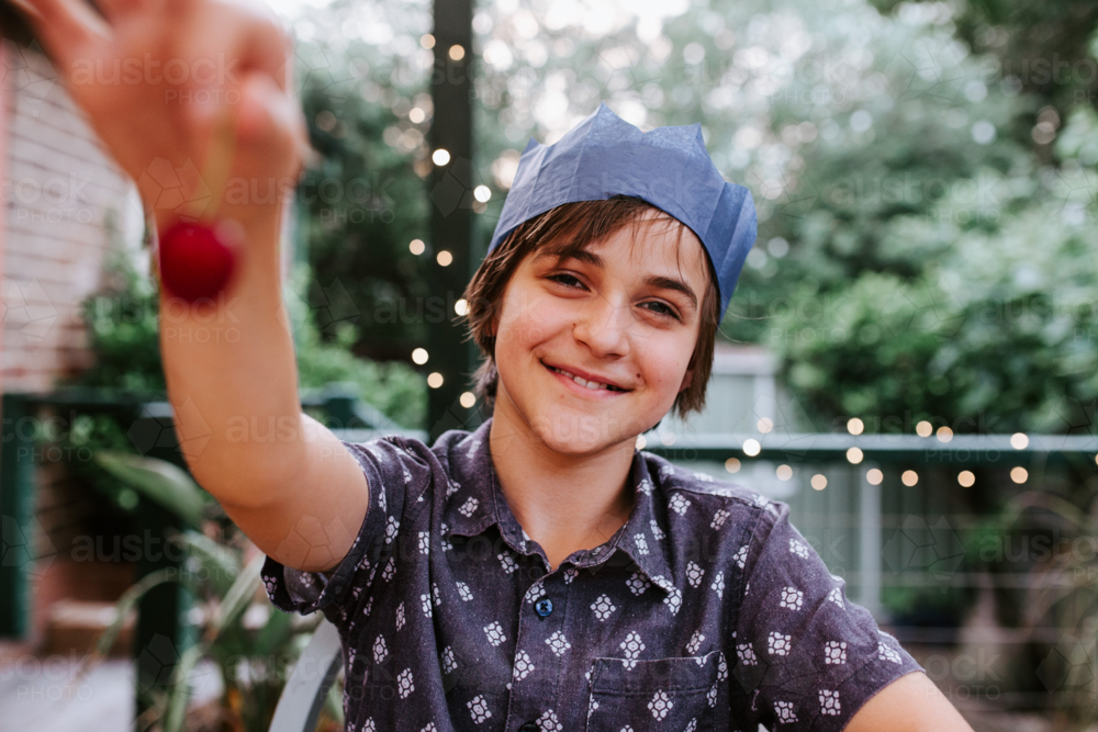 Image of Young boy holding out a cherry smiling - Austockphoto