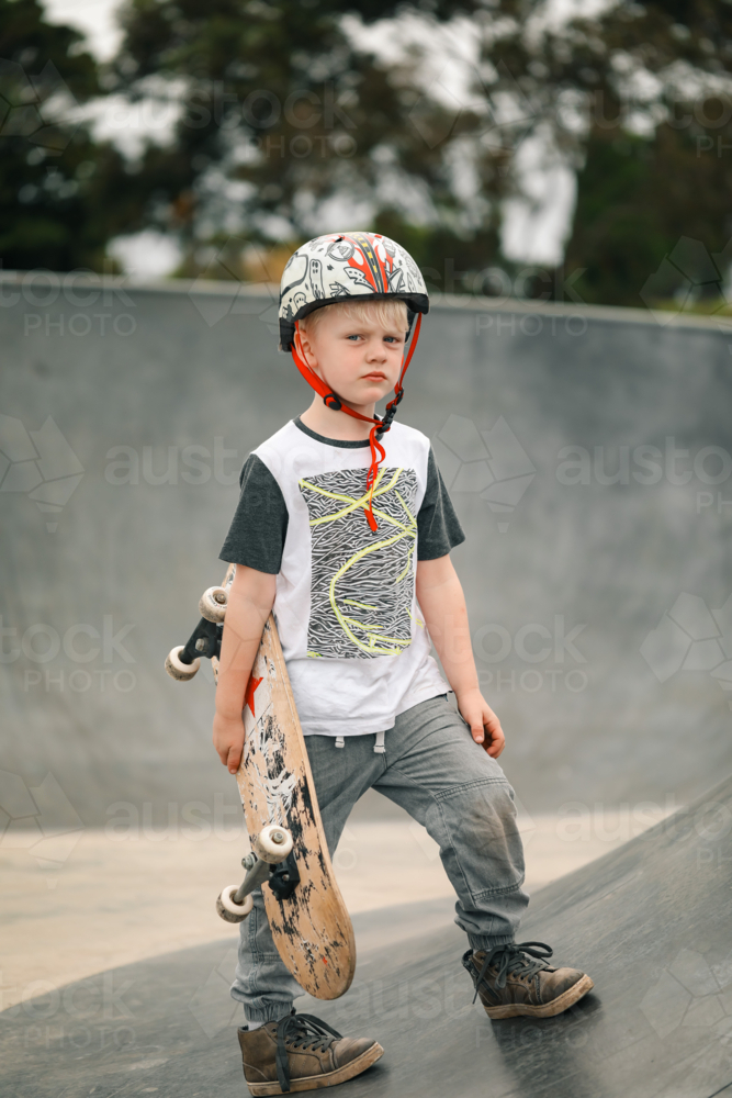 Image of Young boy holding skate board at skate park - Austockphoto