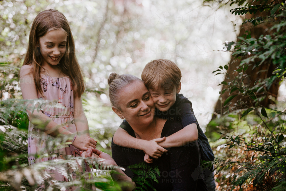 Image of Young boy hugging mum from back in bushland - Austockphoto