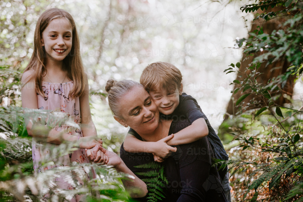 Image of Young boy hugging mum from back in bushland - Austockphoto