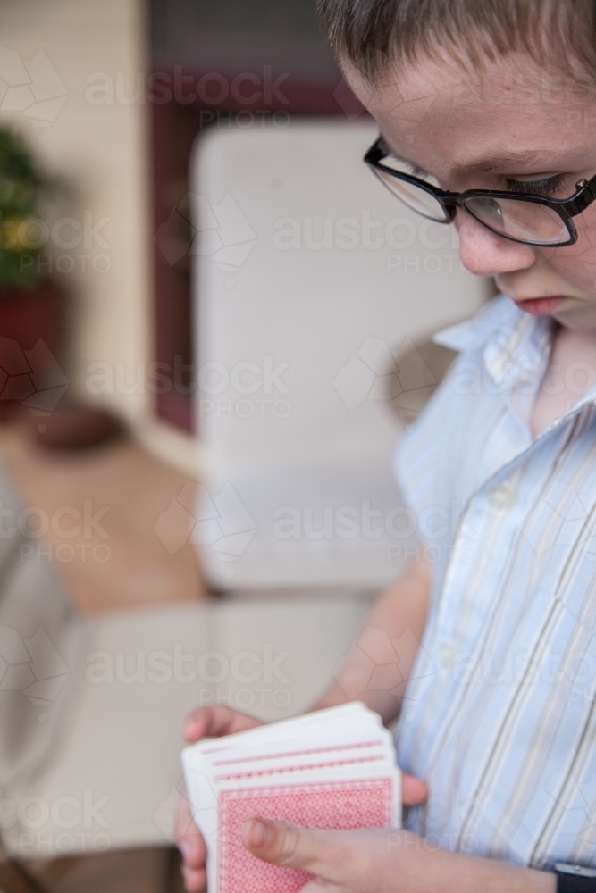 Image of Young boy learning to shuffle cards - Austockphoto