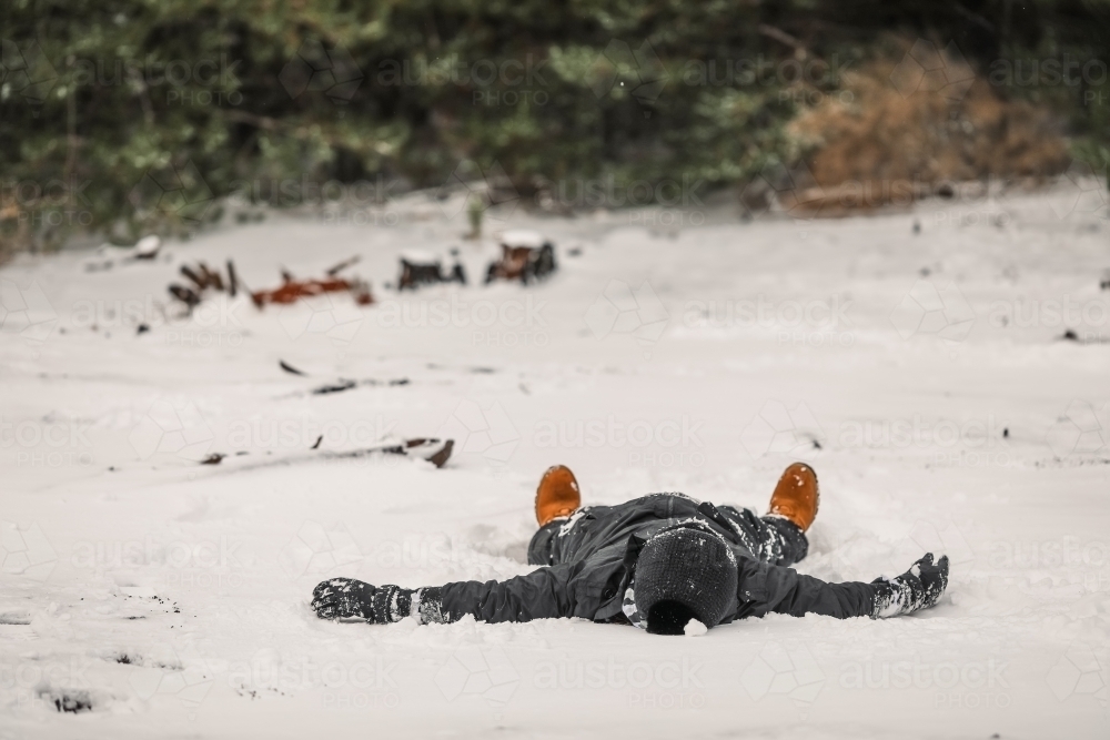 Image of Young boy lying on his back in the snow with copy space ...