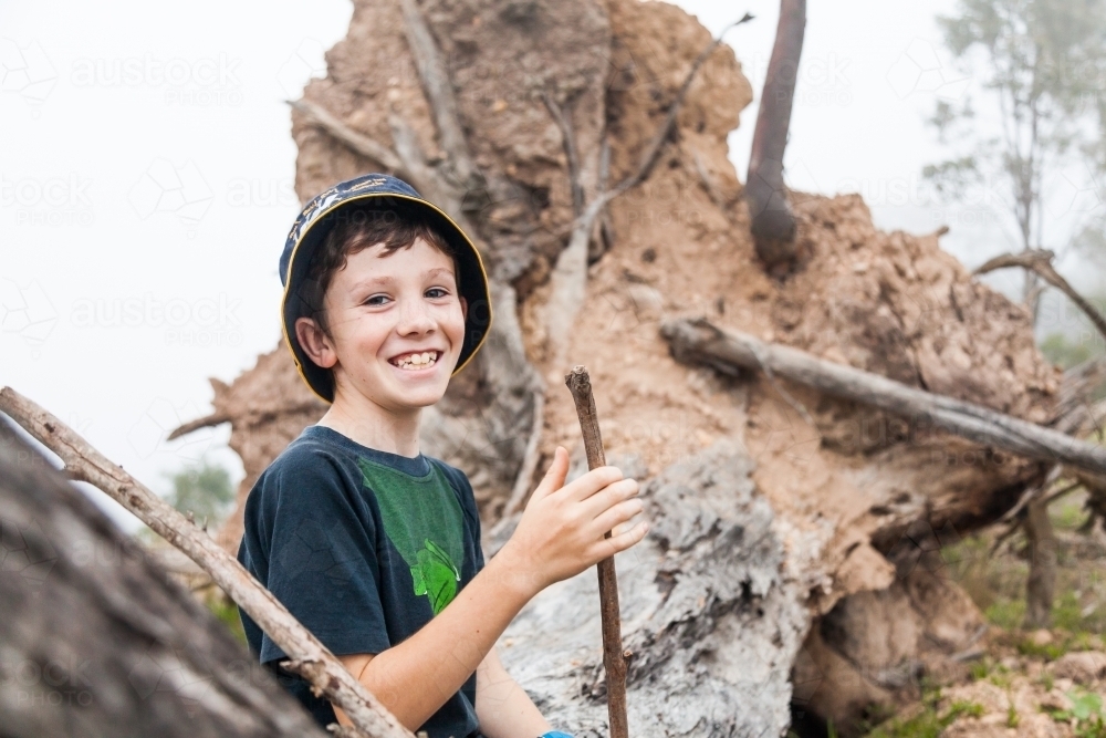 Image of Young boy sitting on a log grinning on misty morning bush walk ...
