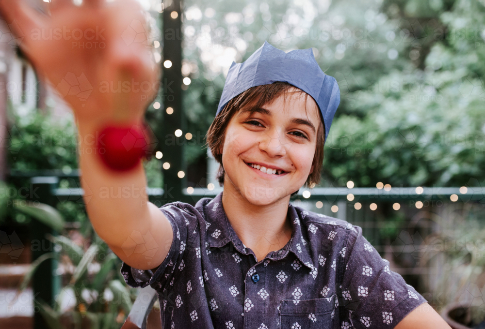 Image of Young boy smiling and holding out a fresh cherry. - Austockphoto
