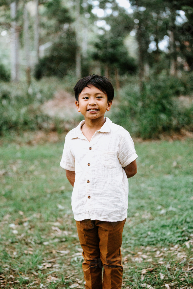 Image of Young boy standing in grassy park outdoors - Austockphoto