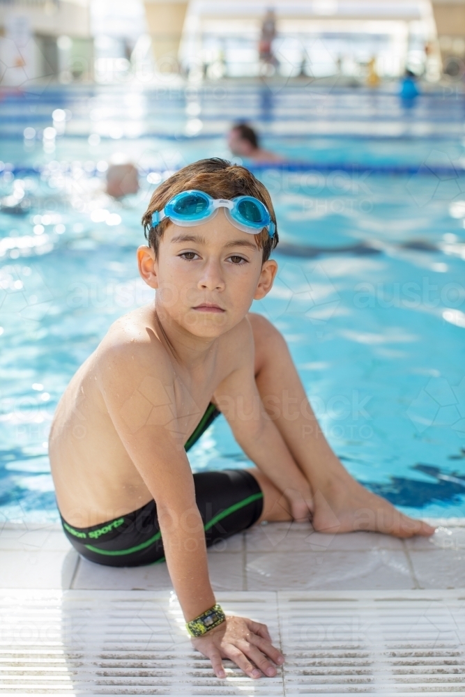 Image of Young boy swimmer sitting at pools edge - Austockphoto