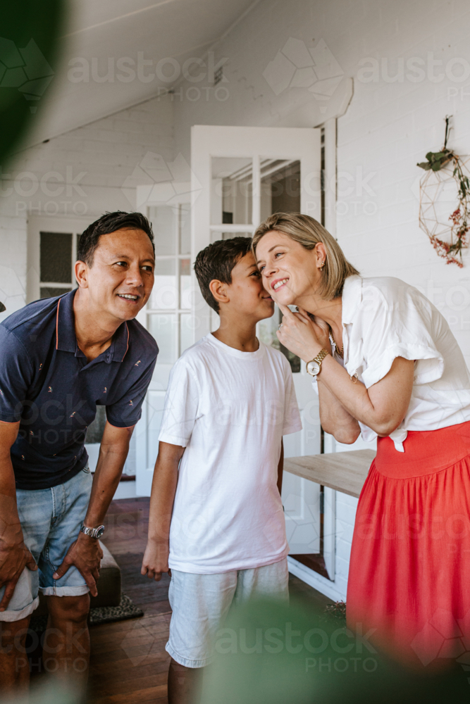 Image of Young boy whispering to her mothers ears while father ...
