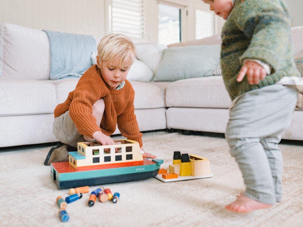 Image of Young boys playing with wooden ferry toy on carpeted floor ...