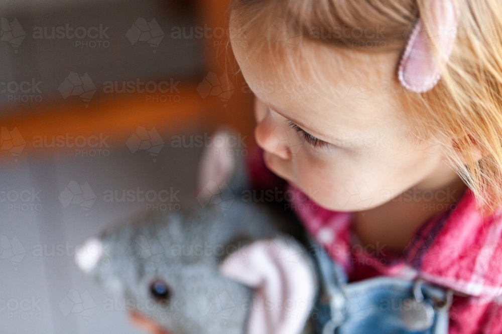 Image of young child cuddling a plush toy possum - Austockphoto