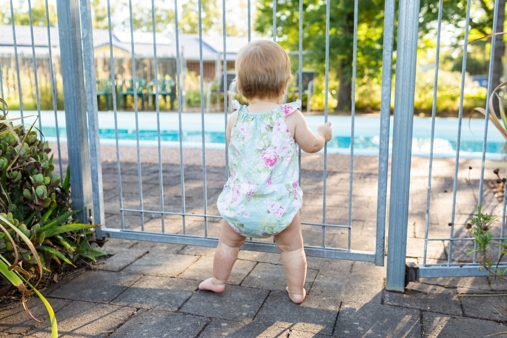 Image of Young child standing at self closing pool gate safe behind ...