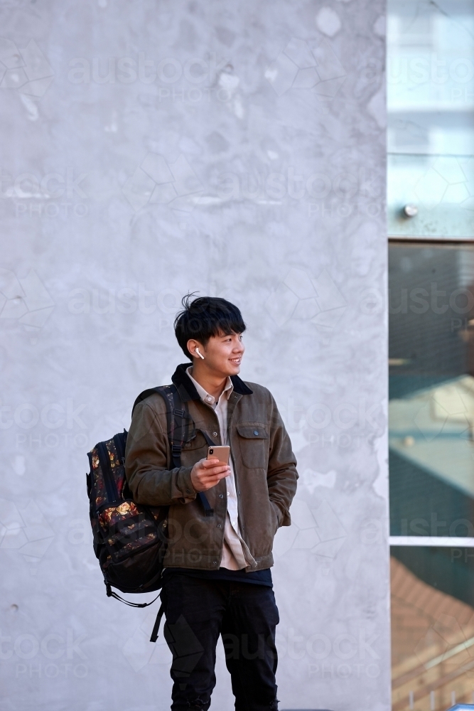 Image of Young Chinese university student standing using mobile phone ...