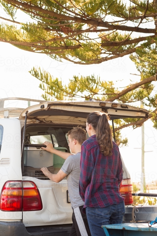 Image of Young couple opening back of 4WD vehicle - Austockphoto
