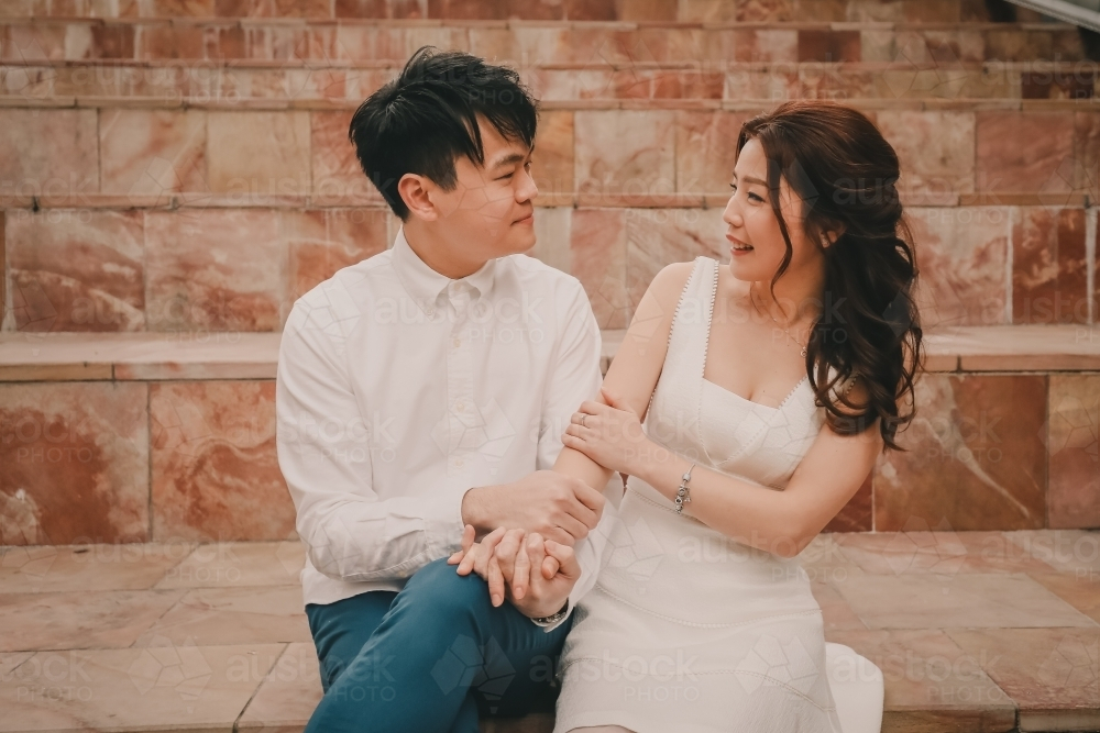 Image of Young couple sitting together on steps at Federation Square ...