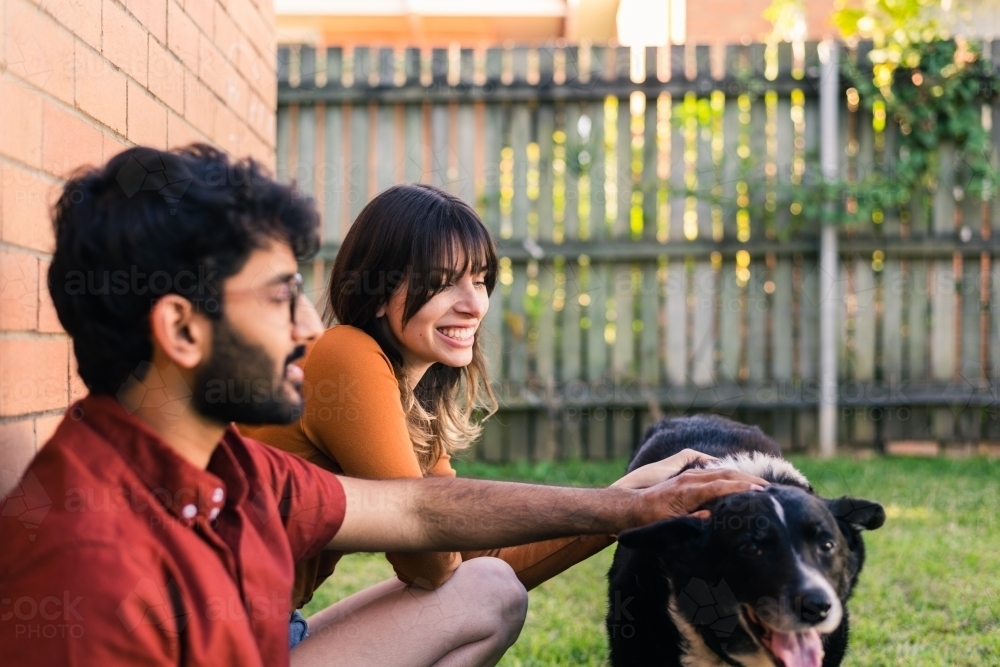 Image of young couple with their dog in the back yard - Austockphoto