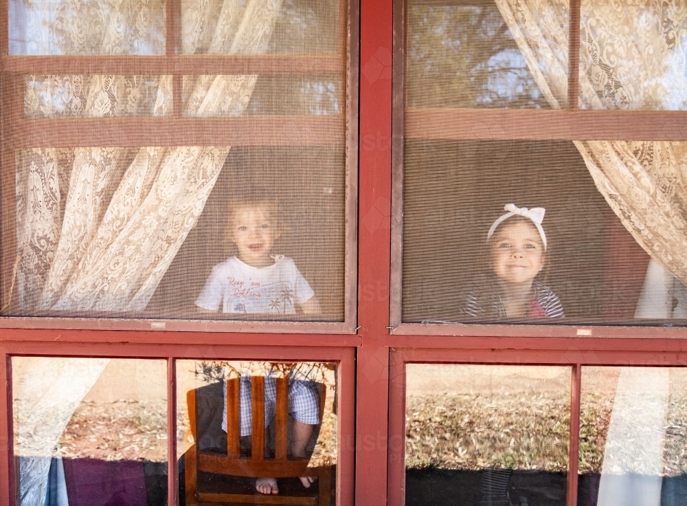 Image of Young cousins looking out a window - Austockphoto