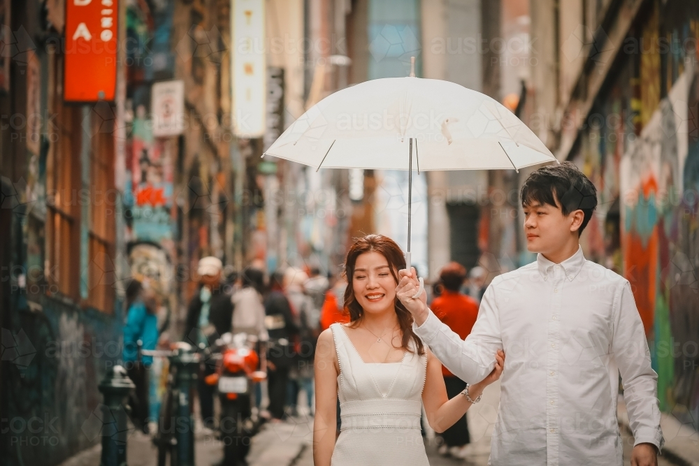 Image of Young engaged couple posing with white umbrella in Hosier Lane ...