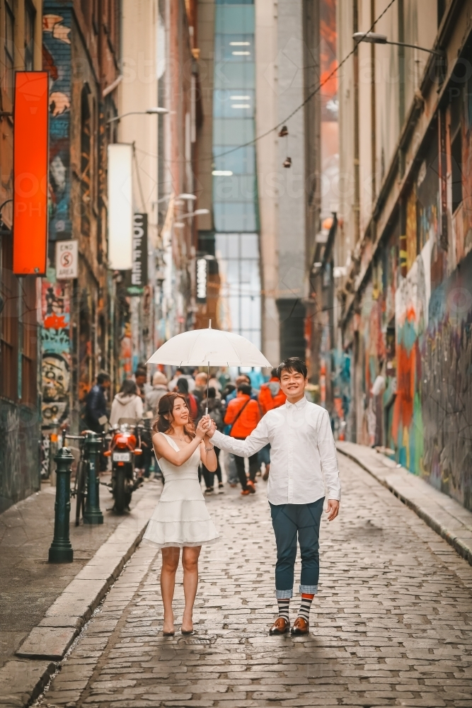 Image of Young engaged couple posing with white umbrella in Hosier Lane ...