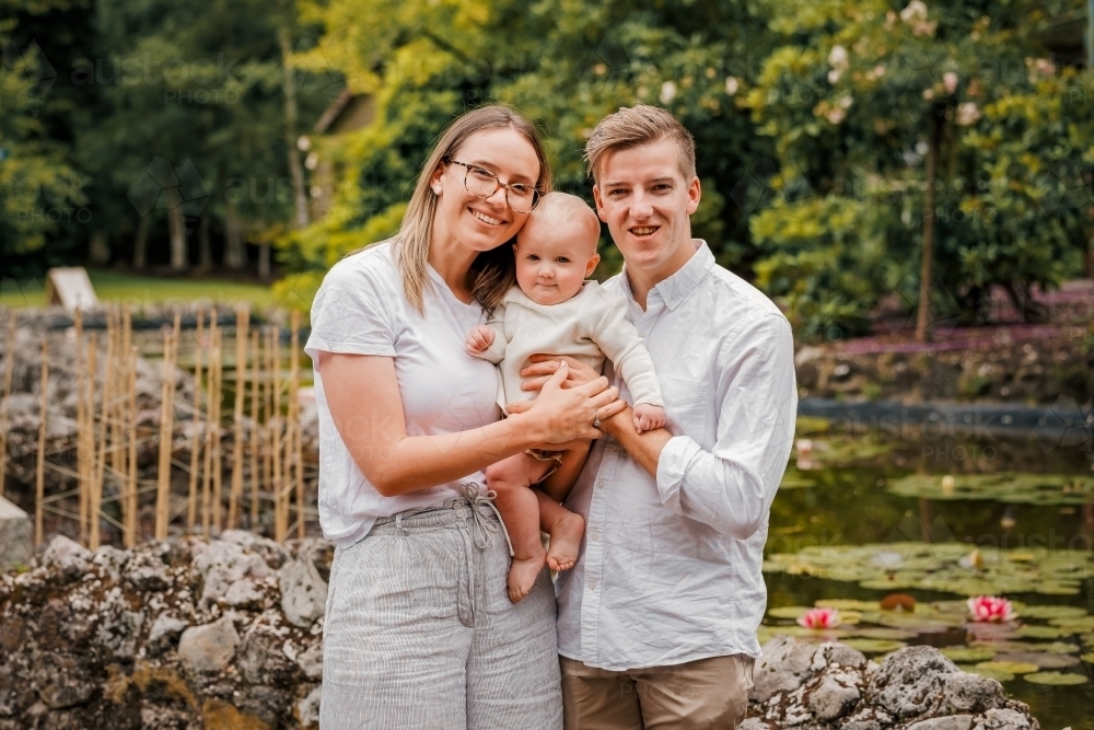 Image of Young family of 3 with small baby at the park - Austockphoto