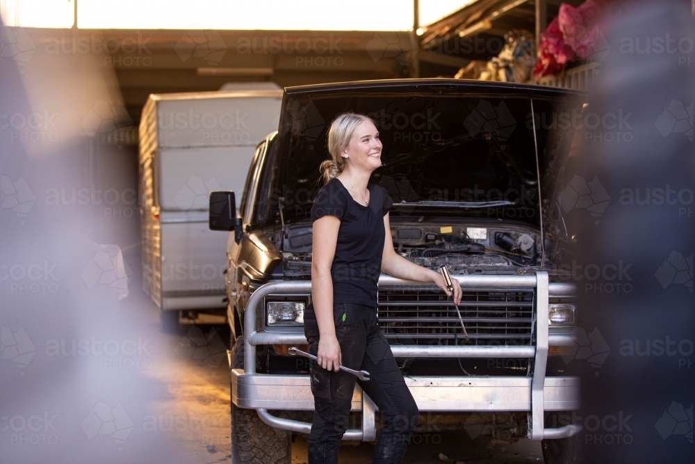 Image of Young female aussie mechanic holding tools and leaning on a ...