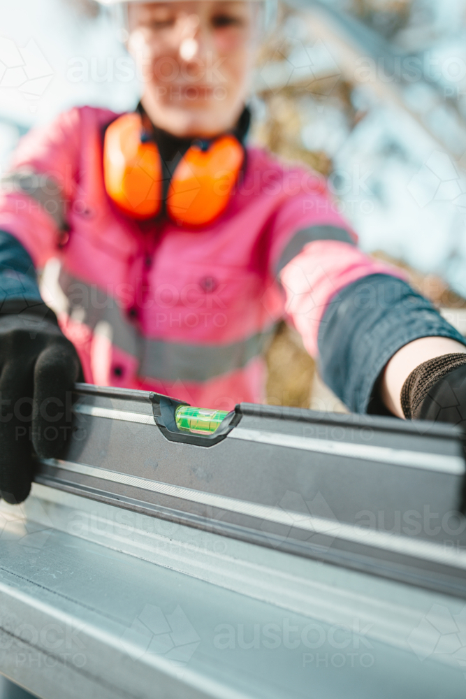 Image of Young female construction worker using her level tool. - Austockphoto