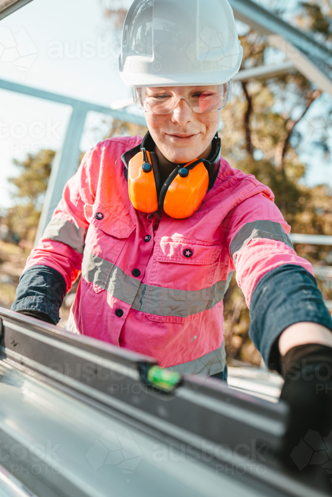Image of Young female construction worker using her level tool ...