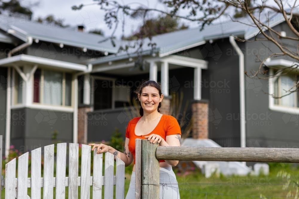 Image of young female homeowner standing smiling at the gate of her ...