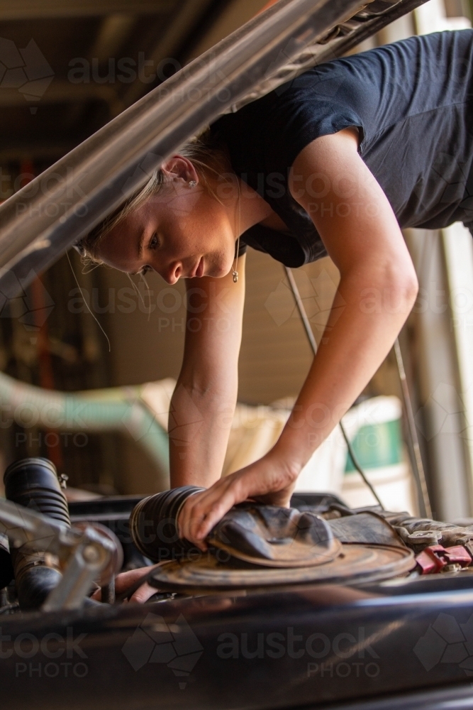 Image of young female tradesperson mechanic fixing car engine in ...