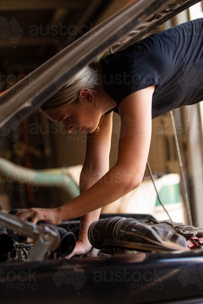 Image of young female tradesperson mechanic fixing car engine in ...