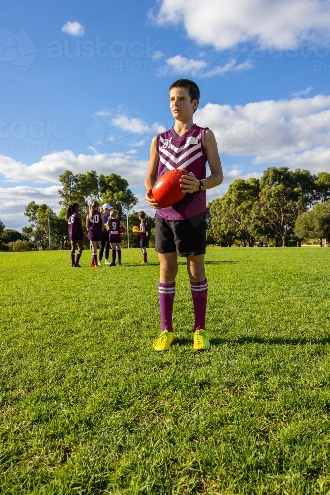 Image of young footballer standing on field with teammates behind ...