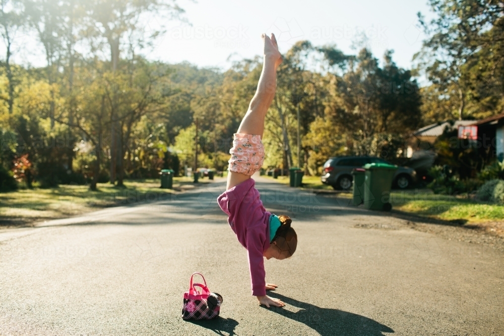 Image of Young girl doing a handstand on the road - Austockphoto