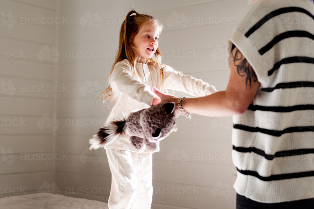 Image of Young girl jumping on the bed while holding mums hand ...