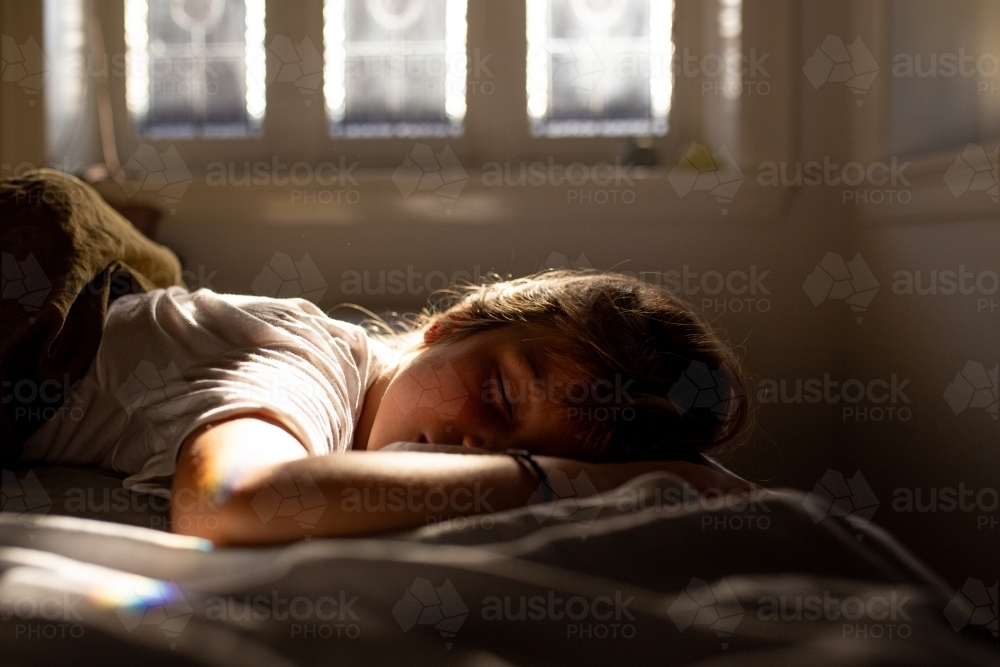 Image of Young girl lying on a bed with their arms stretched out under ...