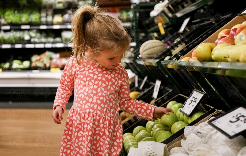 Image of Young Girl Picking Fruits in Supermarket - Austockphoto
