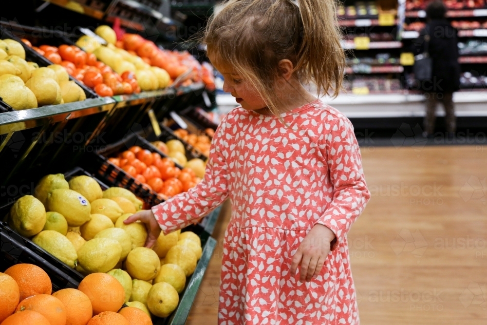 Image of Young Girl Picking Fruits in Supermarket - Austockphoto
