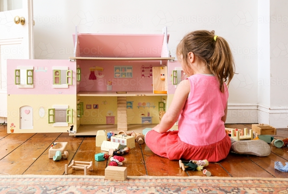 Image of Young girl playing with a dollhouse - Austockphoto