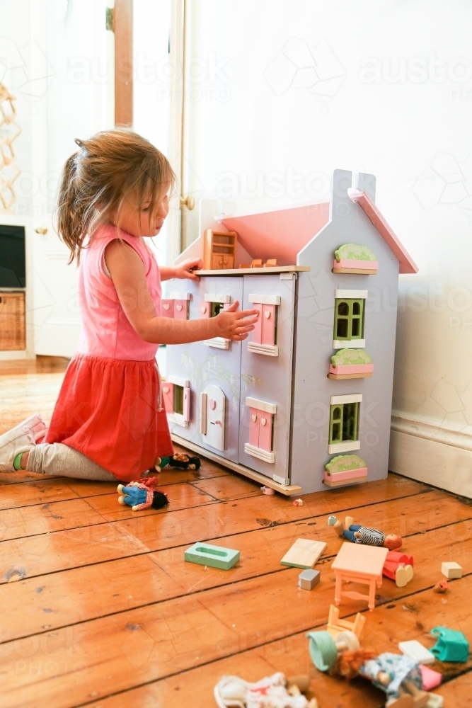 Image of Young girl playing with a dollhouse - Austockphoto