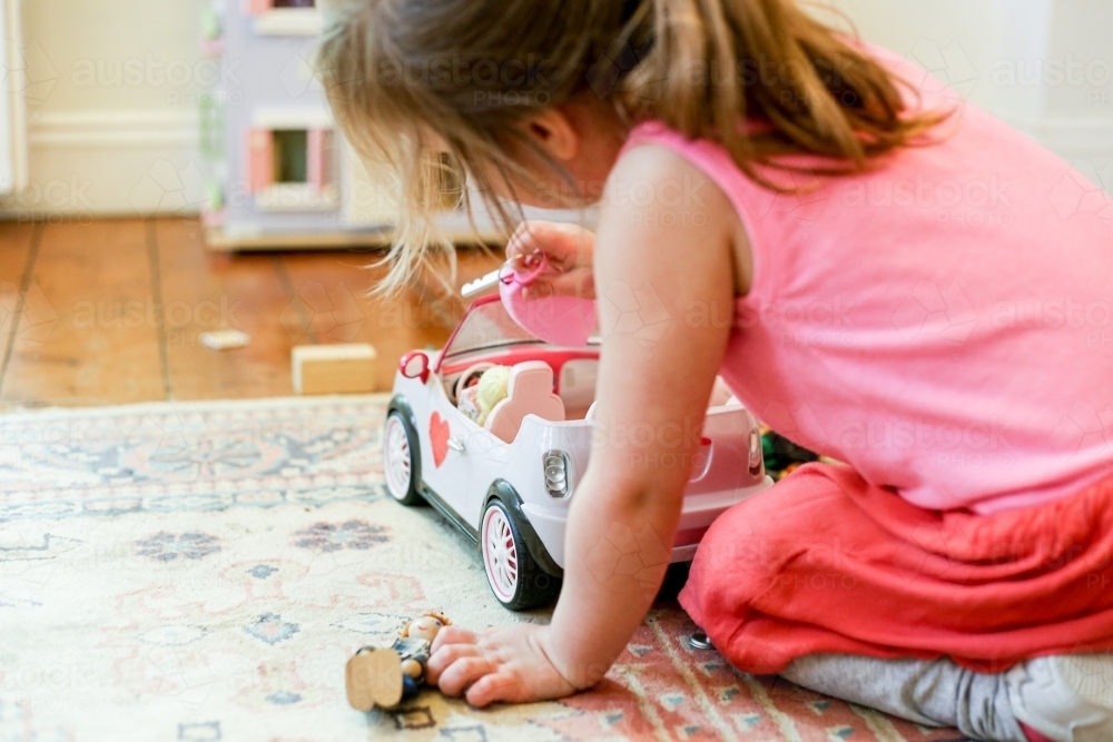 Image of Young girl playing with a toy car - Austockphoto