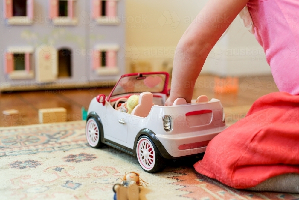 Image of Young girl playing with a toy car with dollhouse - Austockphoto