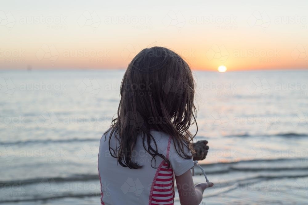 Image of Young girl playing with sand with her back turned facing the ...
